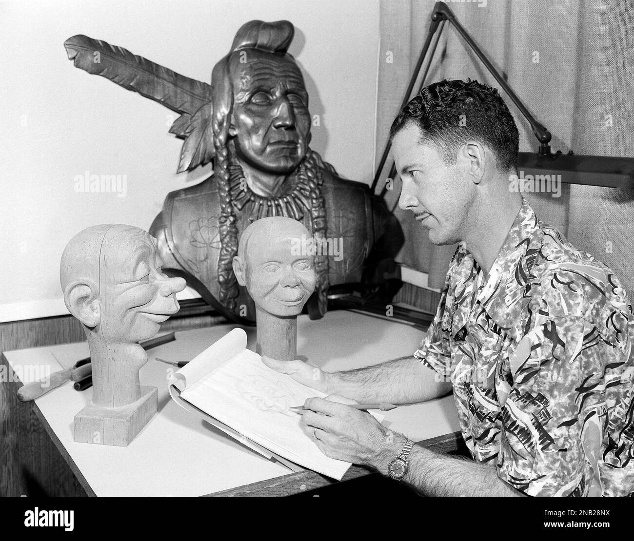 Bob Wallace of Burbank, Calif., at his drawing board, makes a sketch of ...