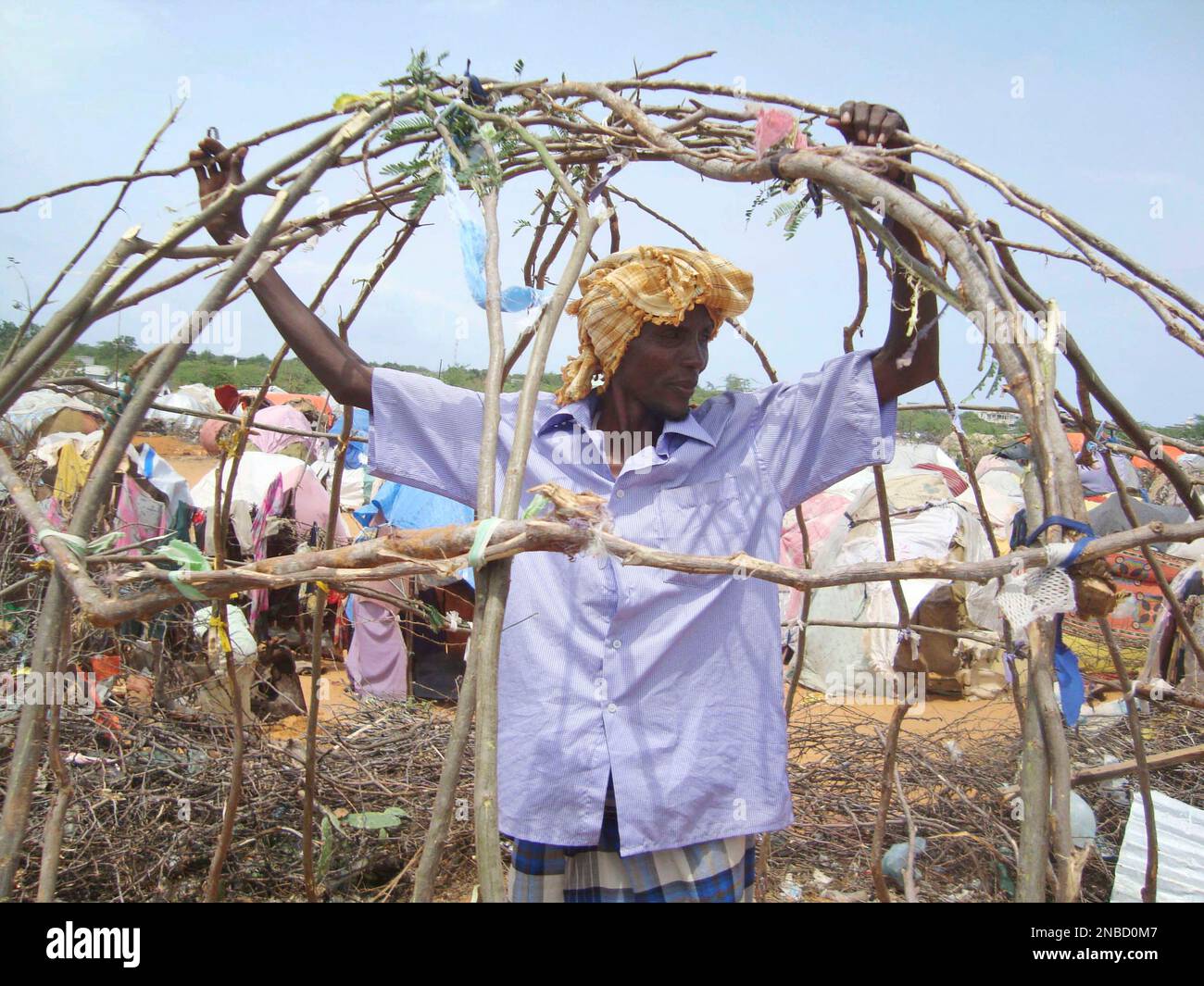 A Somali from southern Somalia constructs a makeshift shelter from tree ...