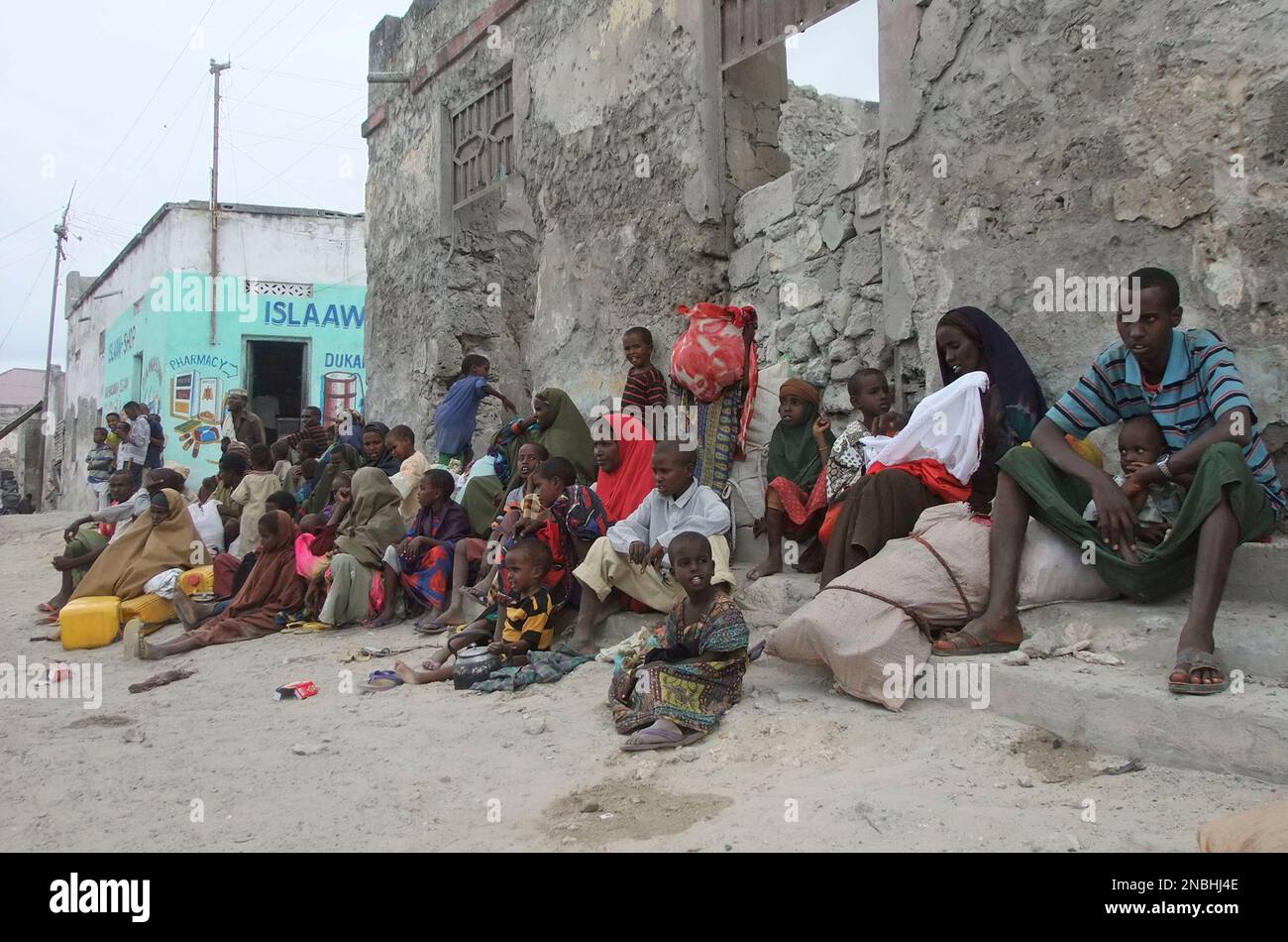 Somalis from southern Somalia, wait outside a ruined building before ...