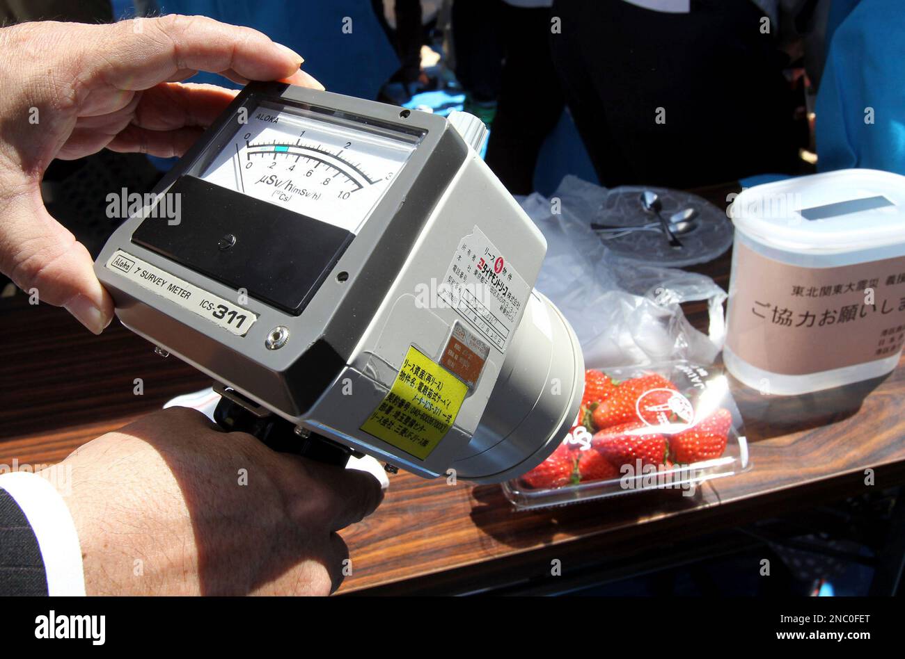 A man uses a radiation detector to measure level of a pack of ...