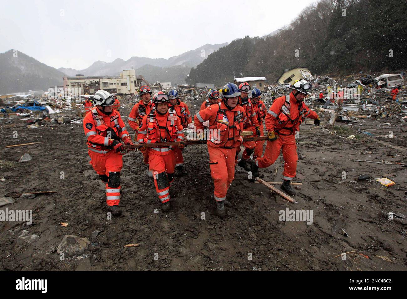 Members of a British search and rescue team carry away the covered body ...