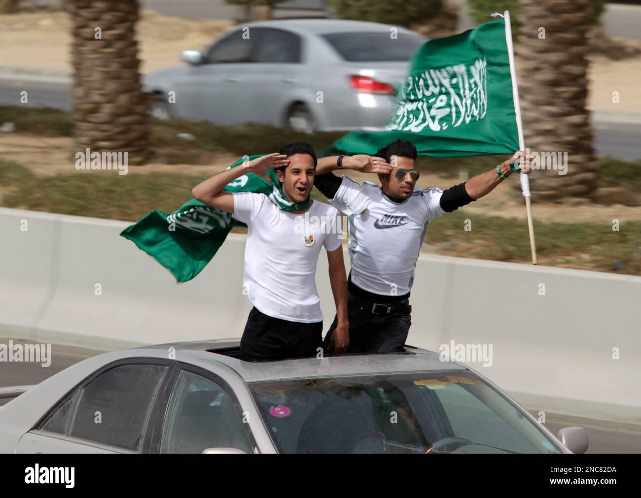 Saudi salute as wave their national flag while riding in a car soon ...