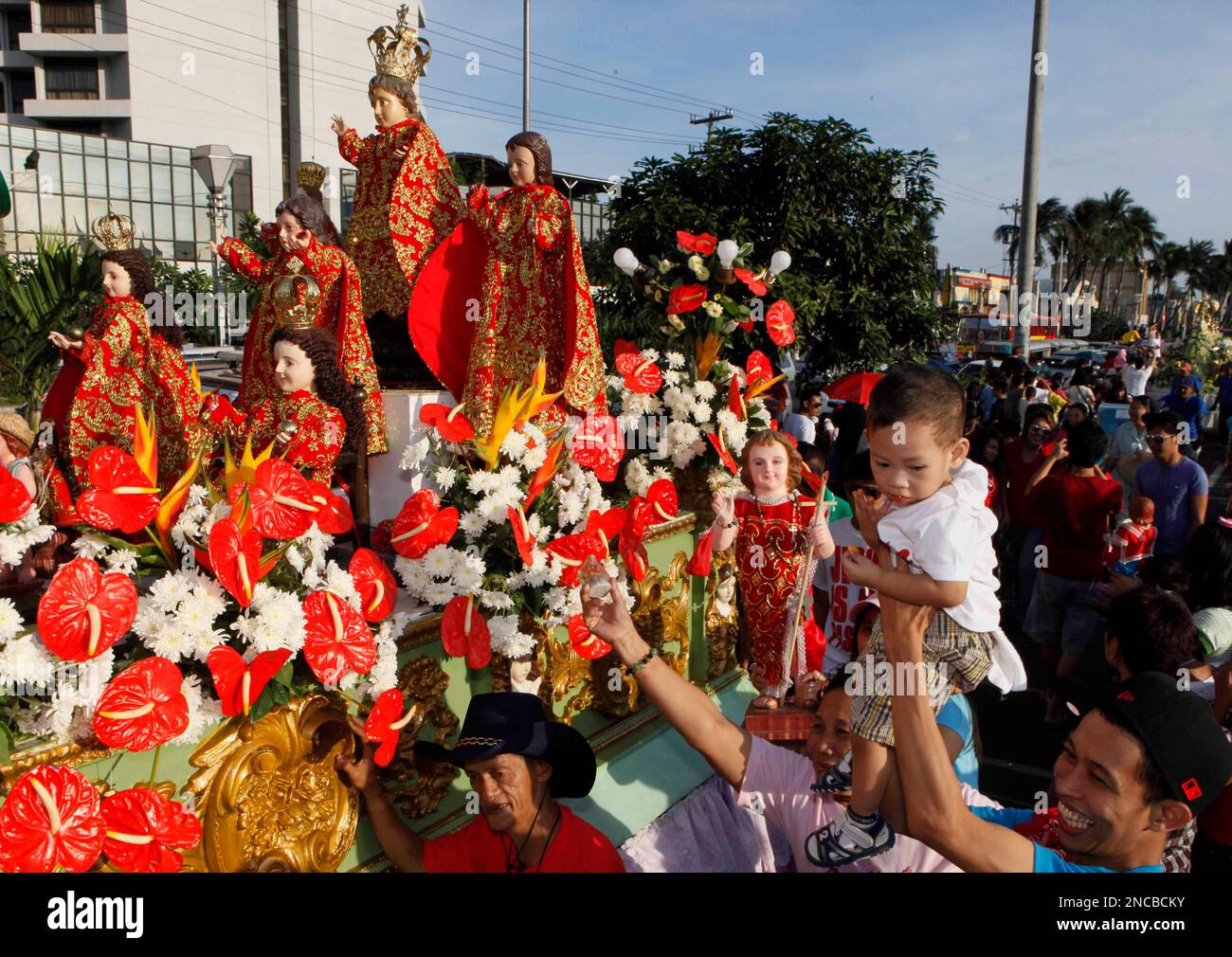 A Catholic devotee lifts his son for a closer look at images of the ...