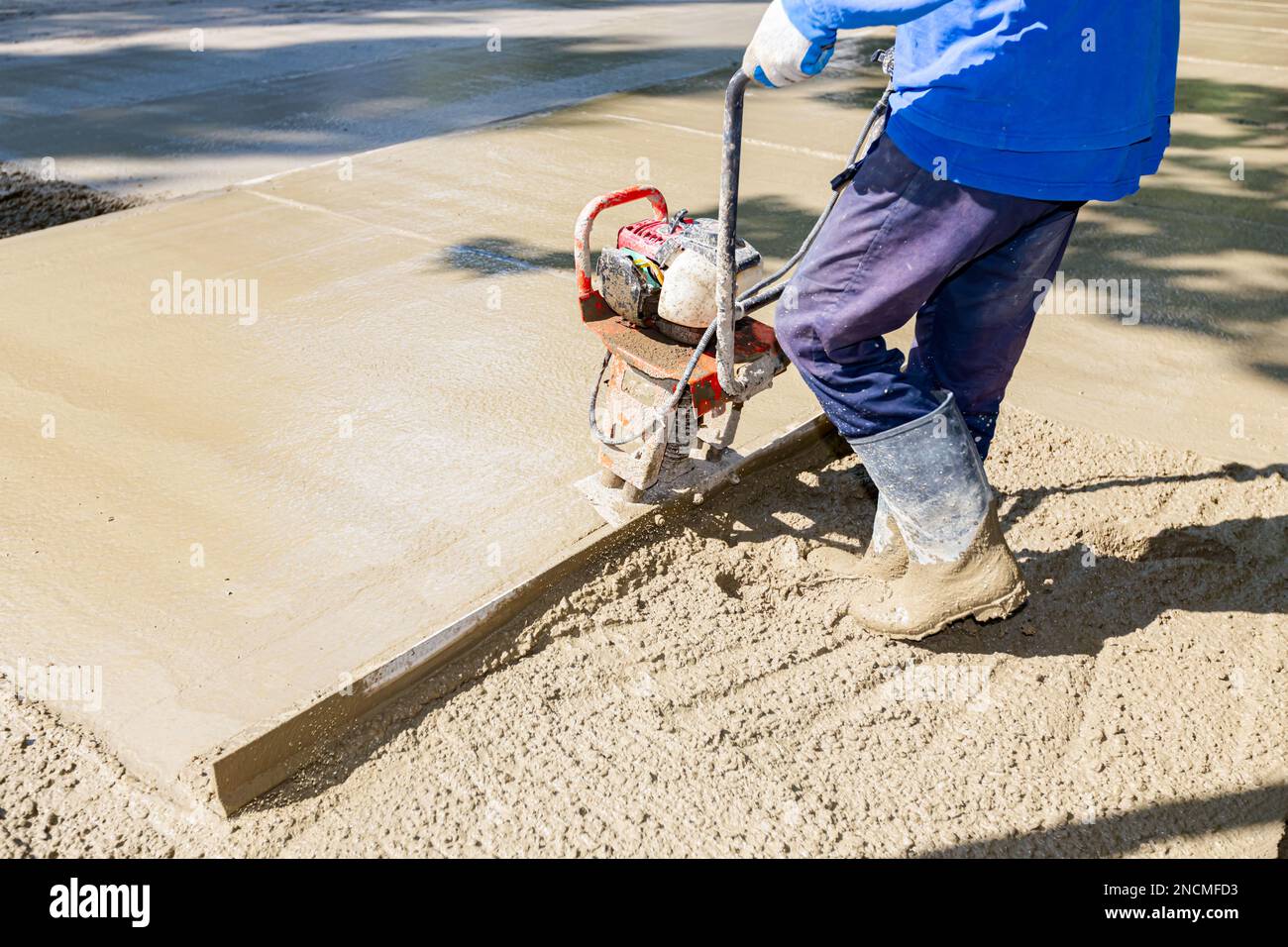 Le travailleur de la construction porte des gants pour niveler le béton ...