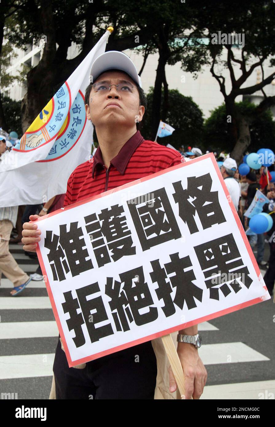 A supporter holds a slogan reading "Protect National Prestige, Refuse ...
