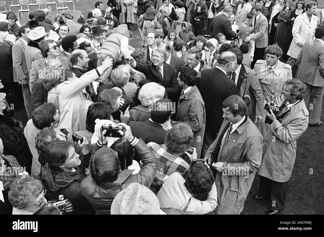President Jimmy Carter hand of a young boy held over the crowd by his ...