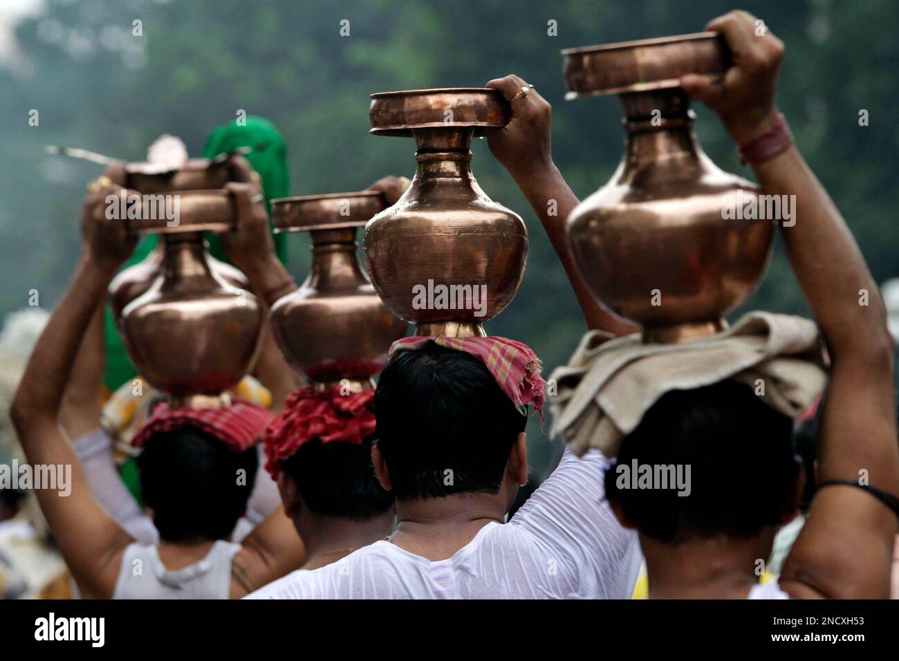 Hindu devotees carry holy water from the Ganges River after performing ...