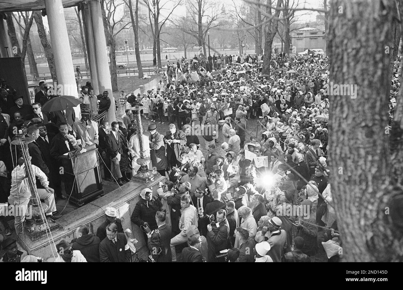 Dr. Martin Luther King Jr., protected by umbrella from rain addresses ...