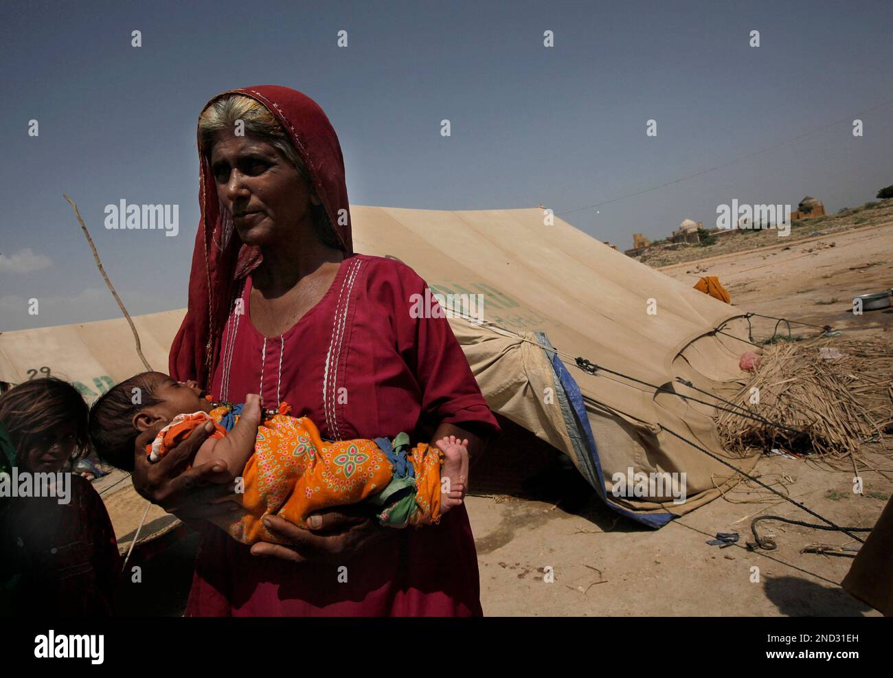 A Pakistani woman who survived floods carries her baby at a temporary ...