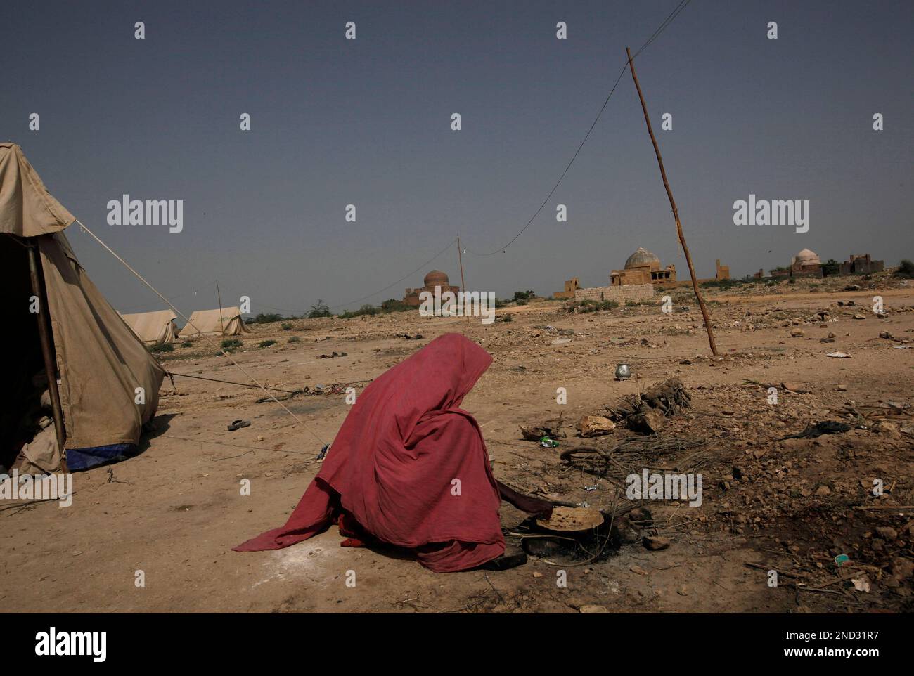 A Pakistani woman who survived floods cooks at a temporary shelters set ...