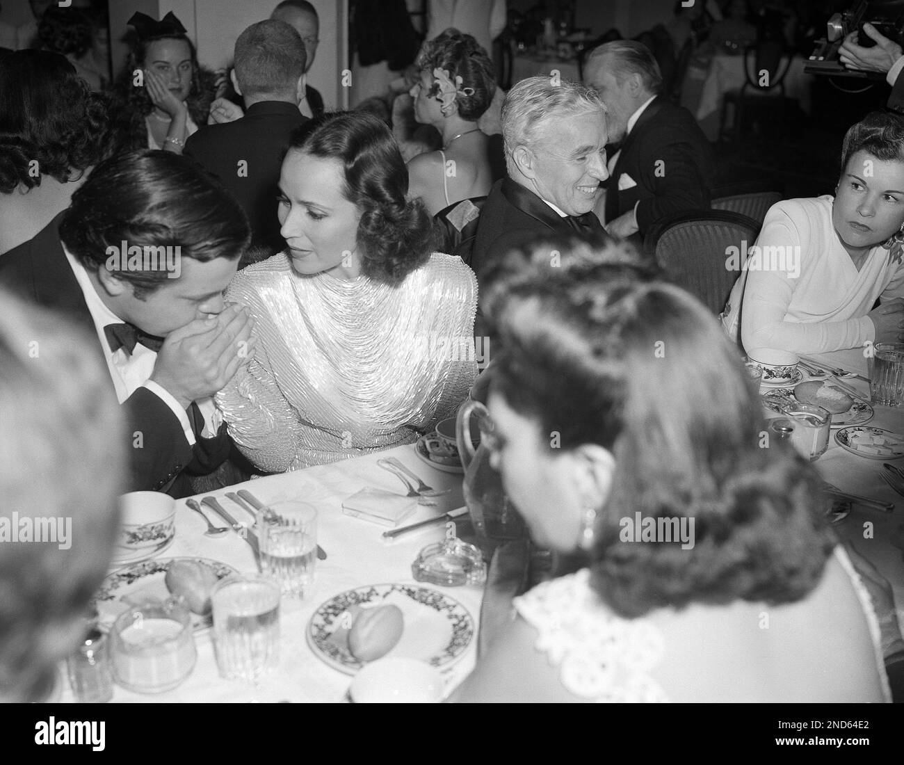 Orson Welles kissing the hand of Dolores del Rio as Charles Chaplin and ...