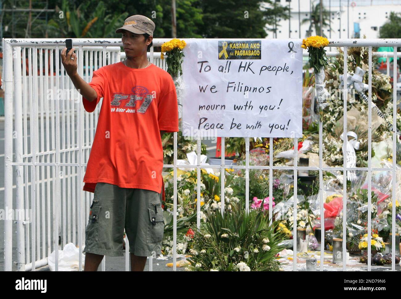 A man takes pictures of himself using his cellphone at the site where ...