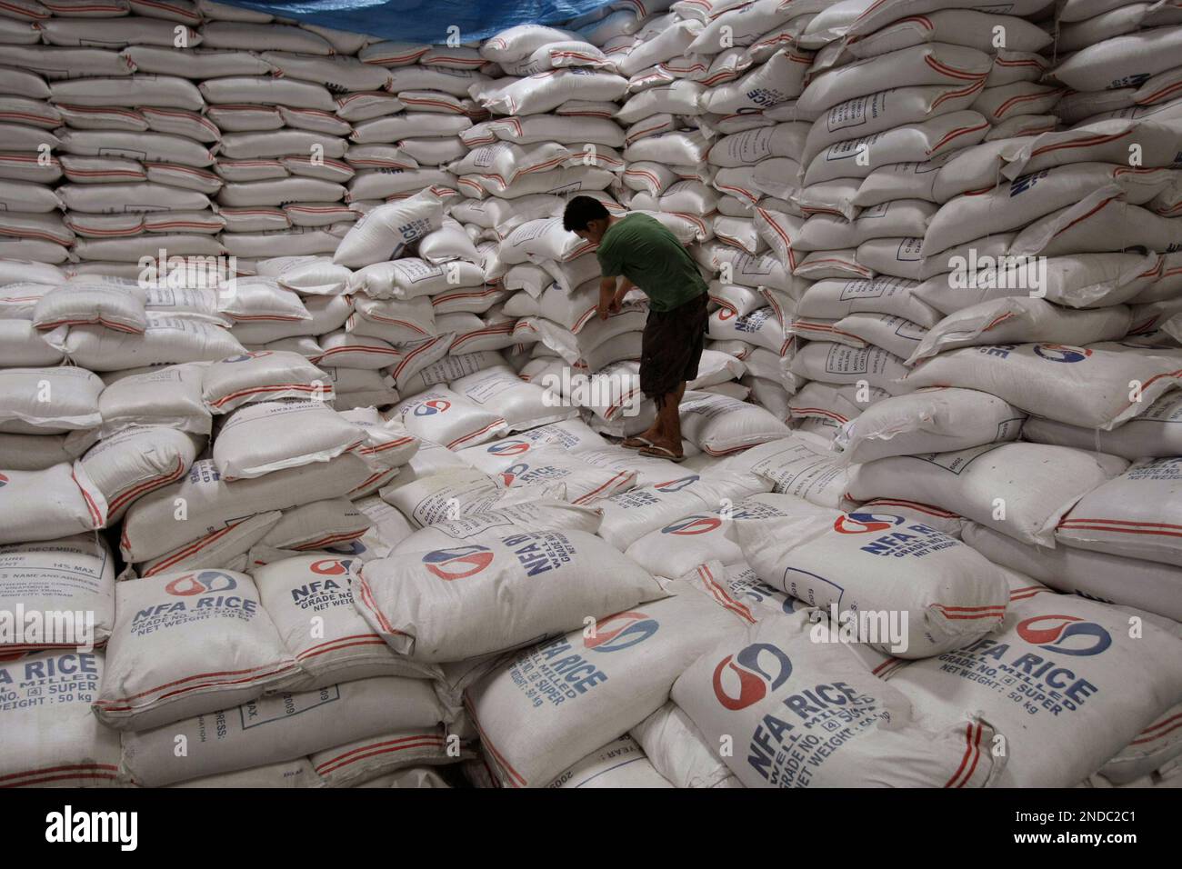 A man works among bags of rice inside a government warehouse Friday ...