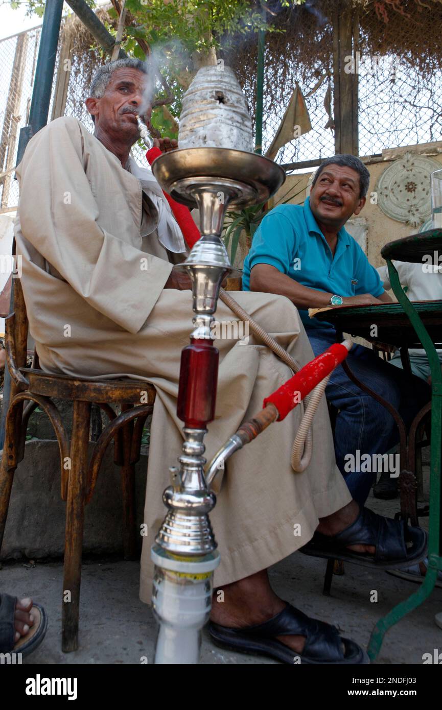 An Egyptian smokes traditional water pipe " Shisha" at a coffee shop in ...