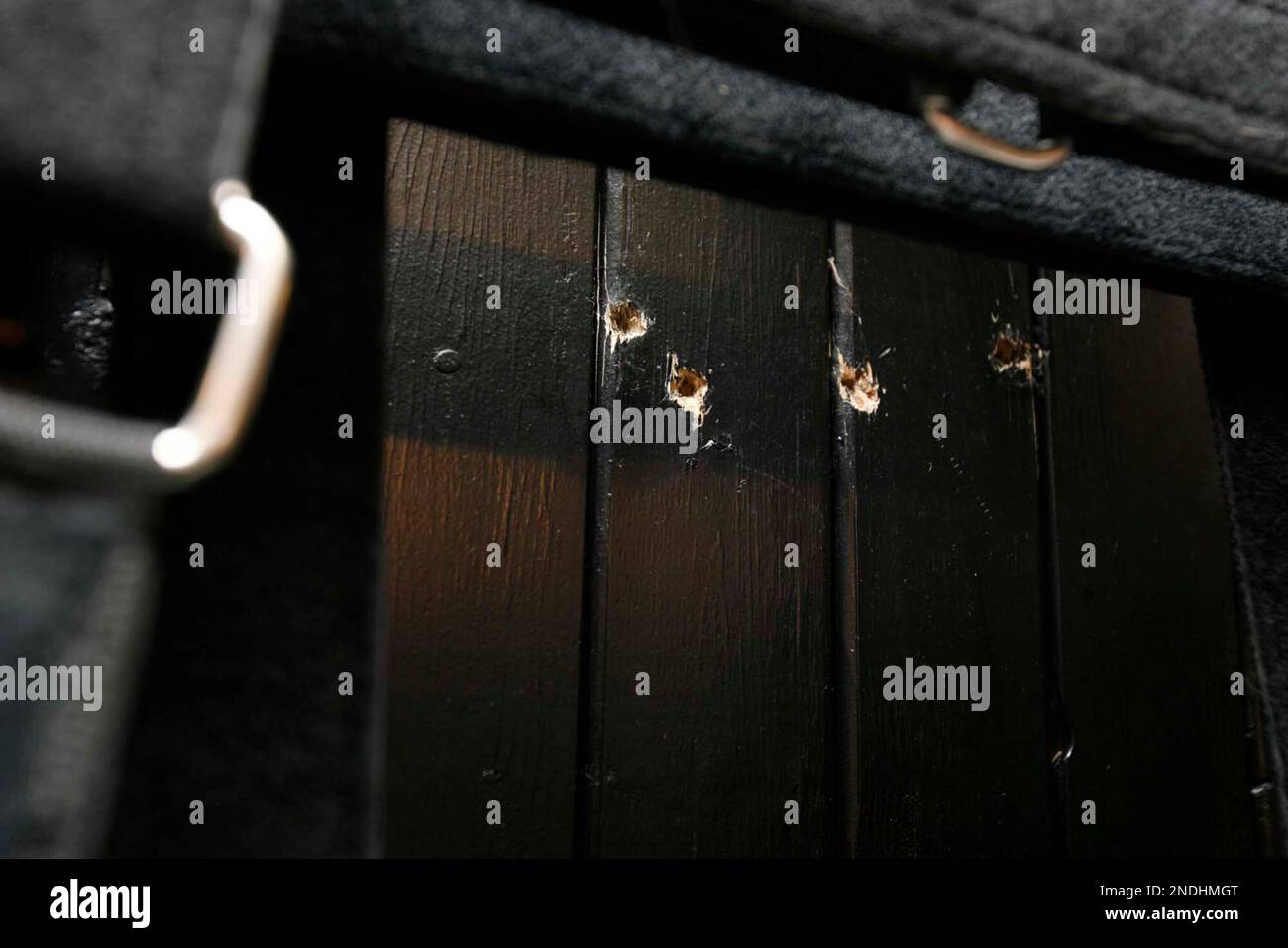 Four bullet holes are visible in the wood panel behind the chair in the ...