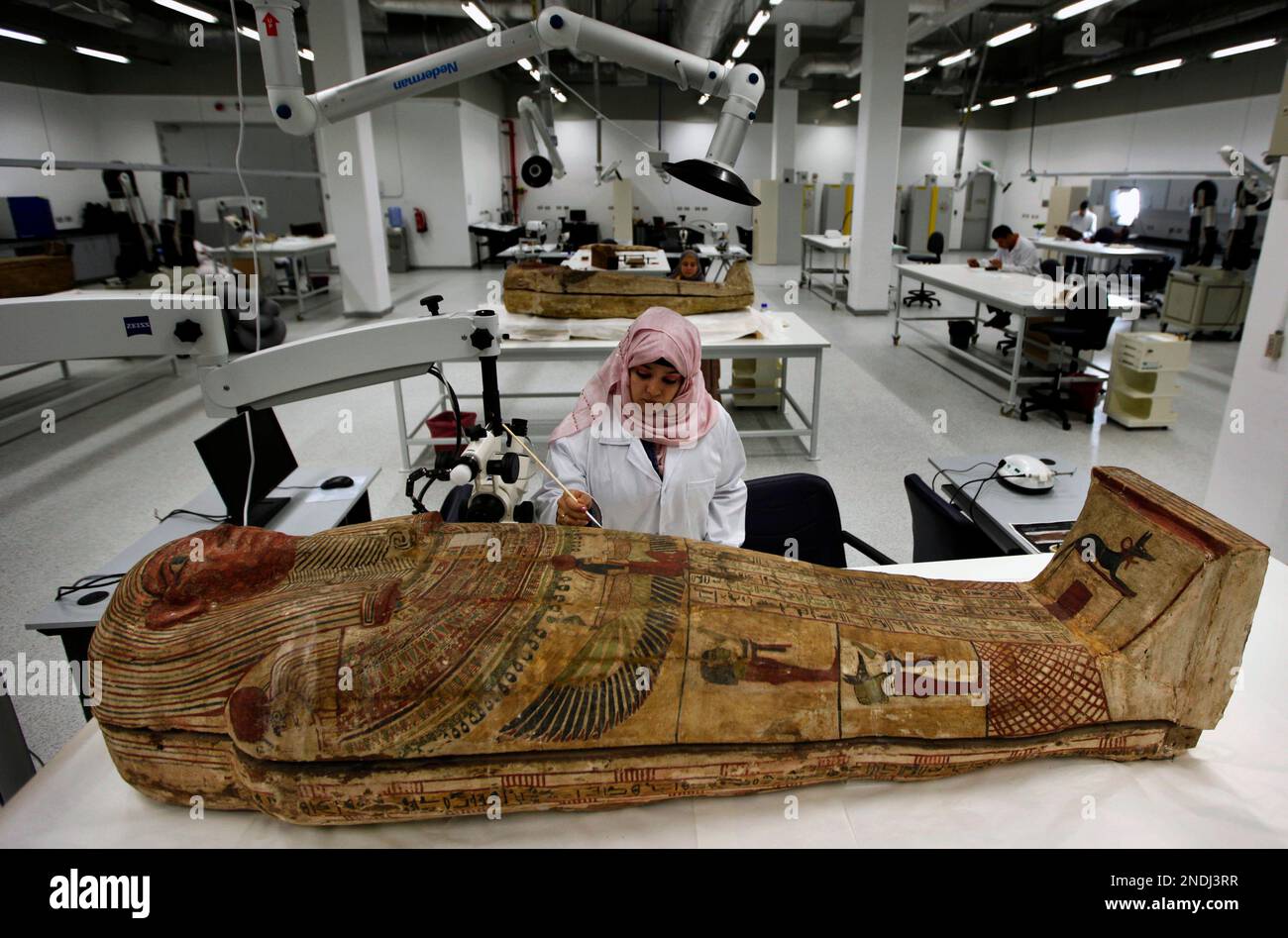 An Egyptian archeological technician works on a wooden sarcophagus case ...