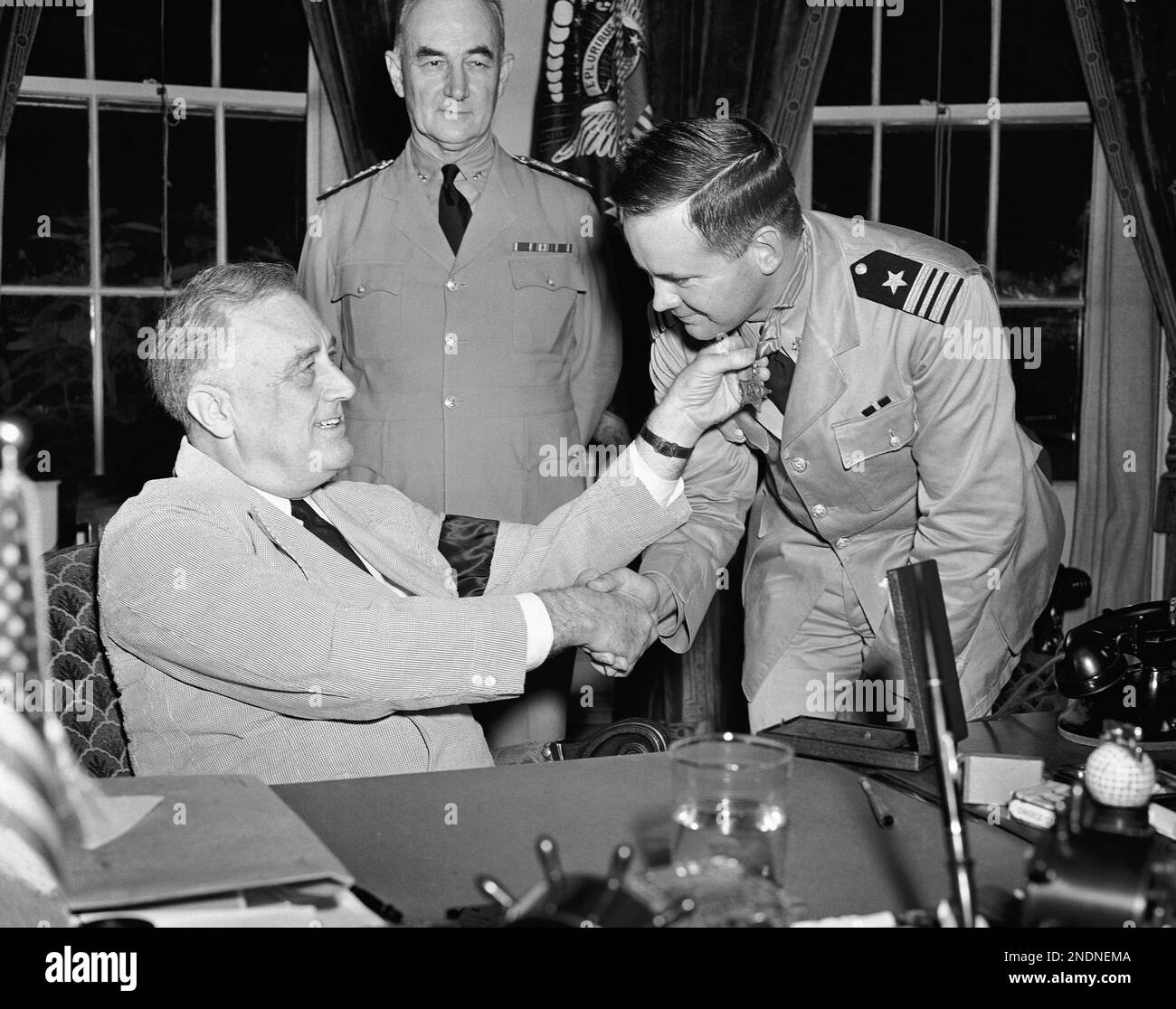 Grasping his right hand, President Franklin D. Roosevelt awards the ...
