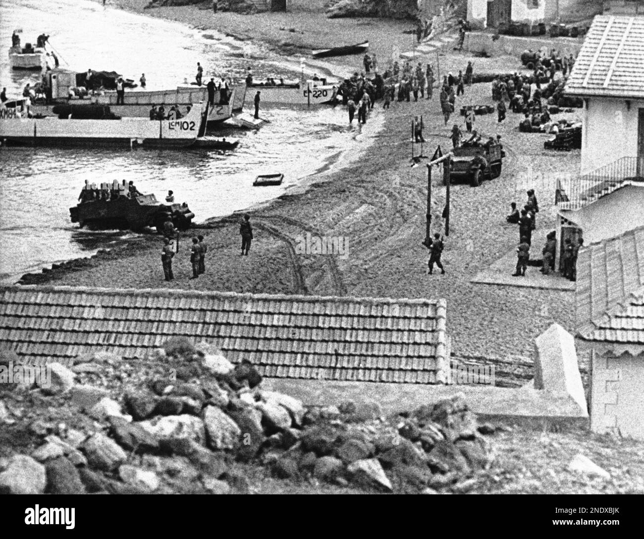 A half-track scout car emerges from the water and grinds up this beach ...