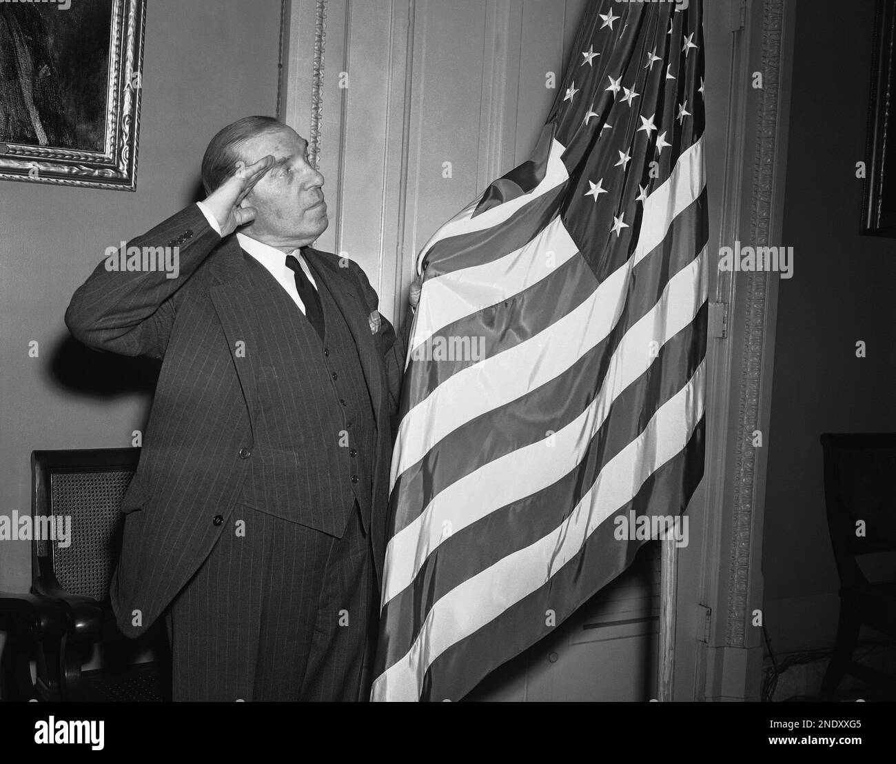 Rep. Sol Bloom (D-NY), salutes a flag made from a substitute for silk ...