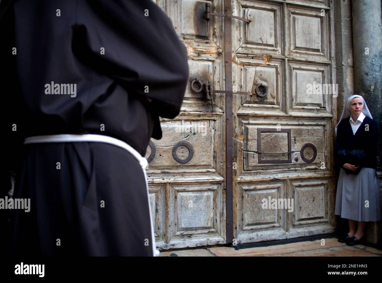 A Catholic nun stands at the locked doors of the Church of the Holy ...