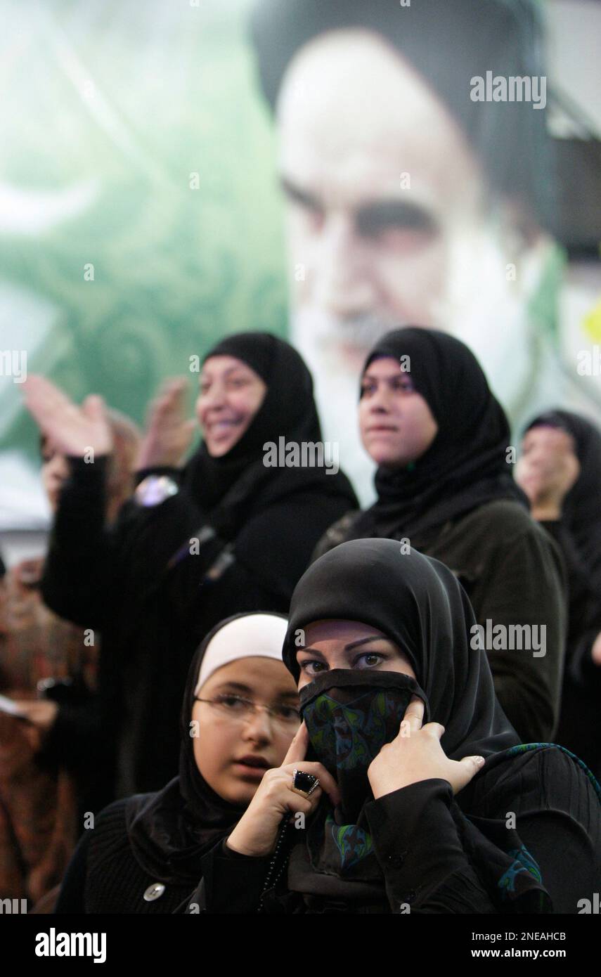A woman, front right, covers her face as others react to the speech of ...