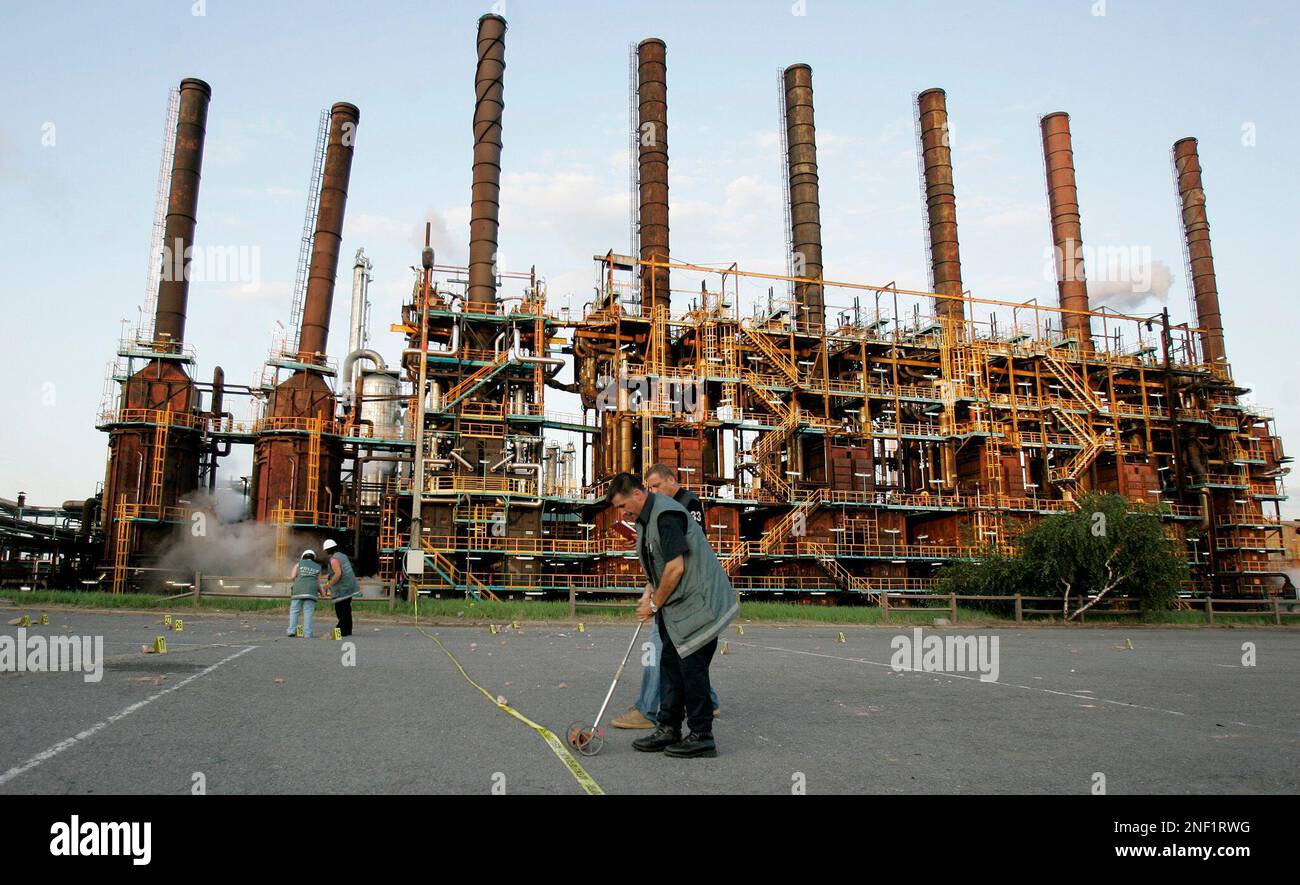 Forensic Police officers work in front of the chimneys at a Total ...