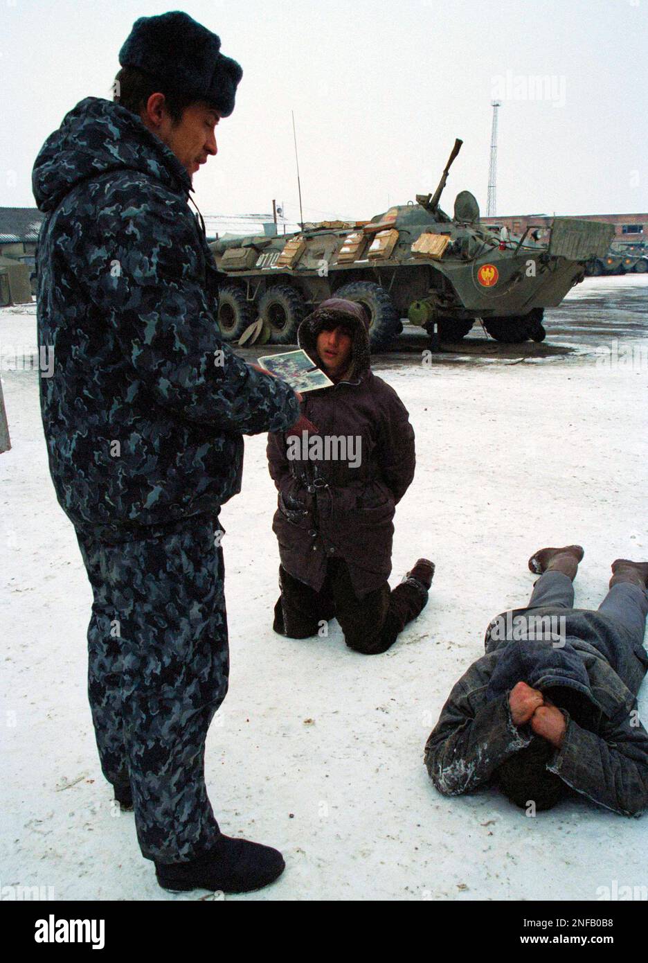 A Chechen civilian lays on the ground and another is on his knees while ...