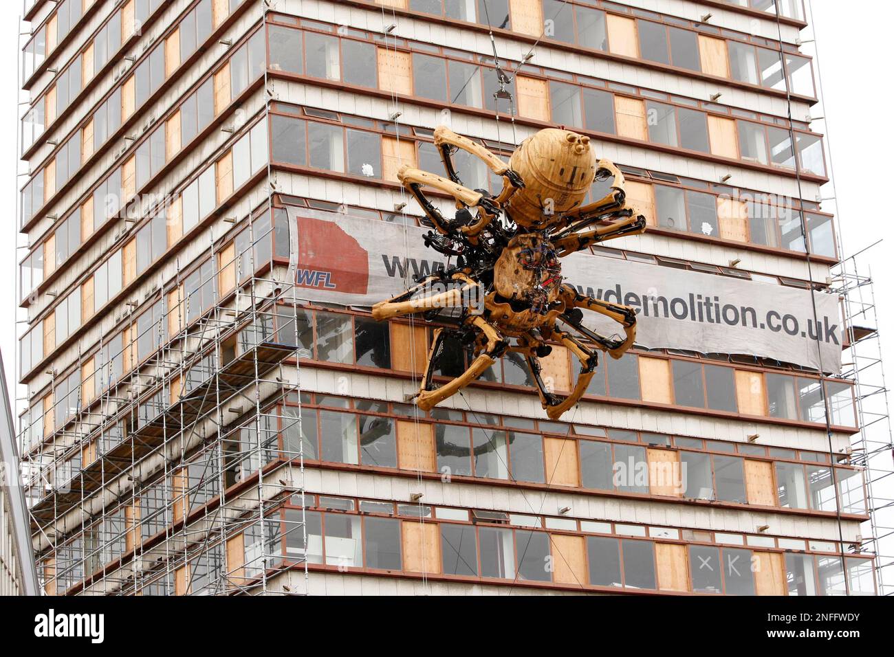 A giant mechanical spider hangs from a disused building in the centre ...