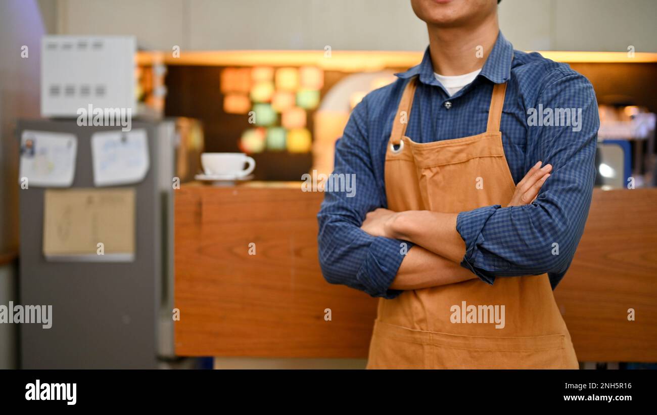 Baristas ou serveur asiatique de talent et de succès dans des stands de tablier avec les bras ...