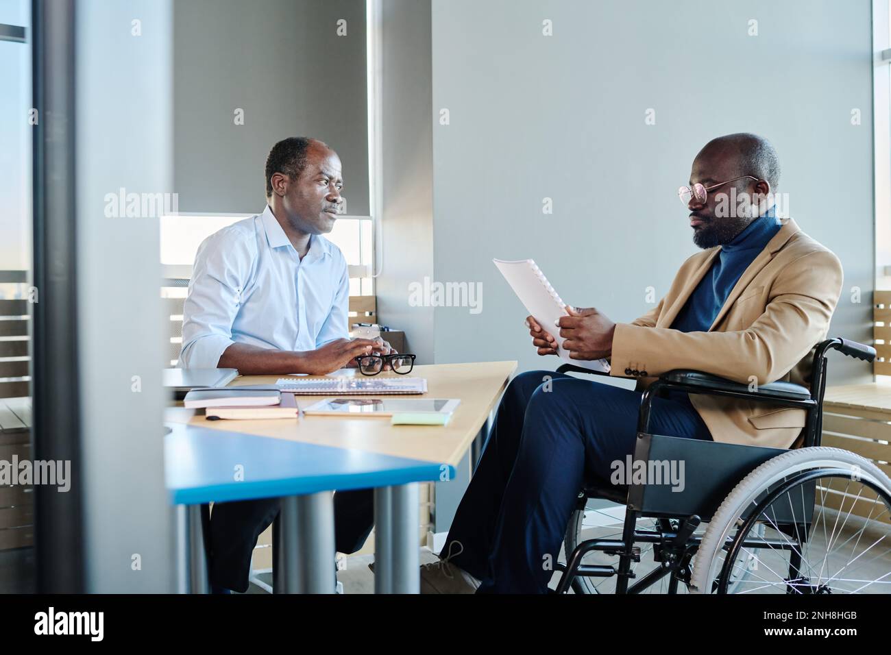 Un jeune économiste masculin handicapé fait rapport à un patron afro ...