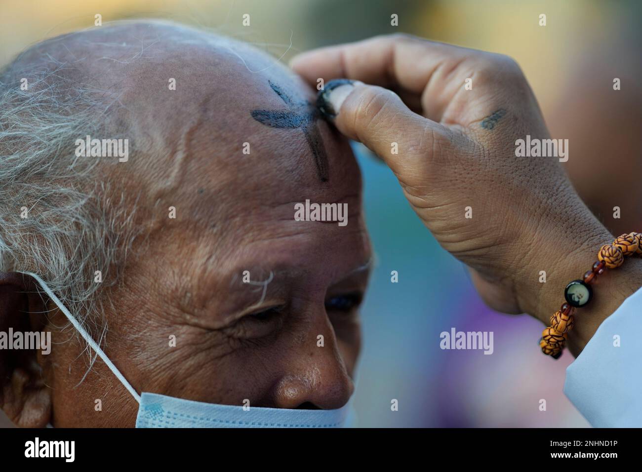 A lay minister places ash on the forehead of a devotee during Ash ...