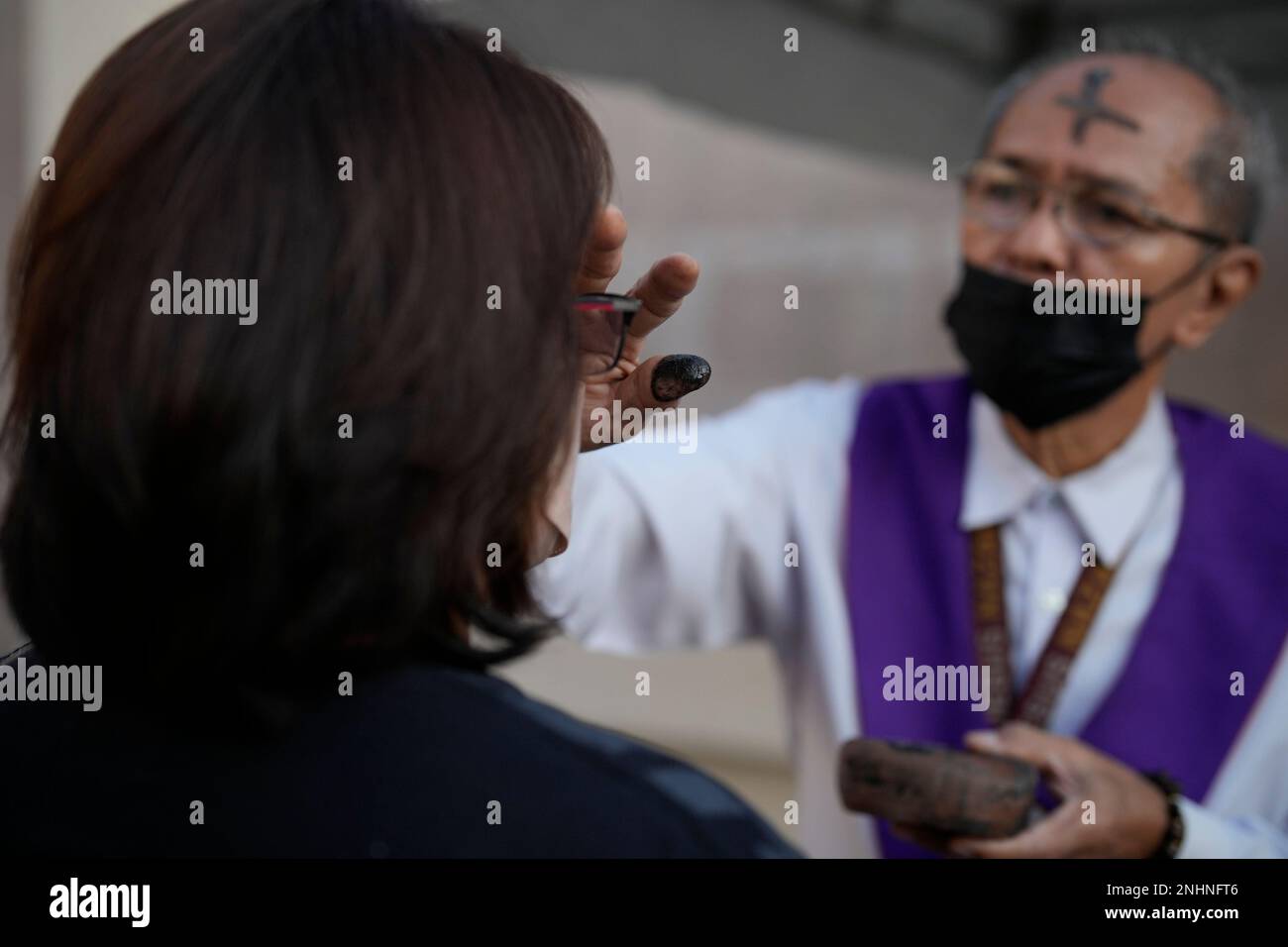 A lay minister places ash on the forehead of a devotee during Ash ...