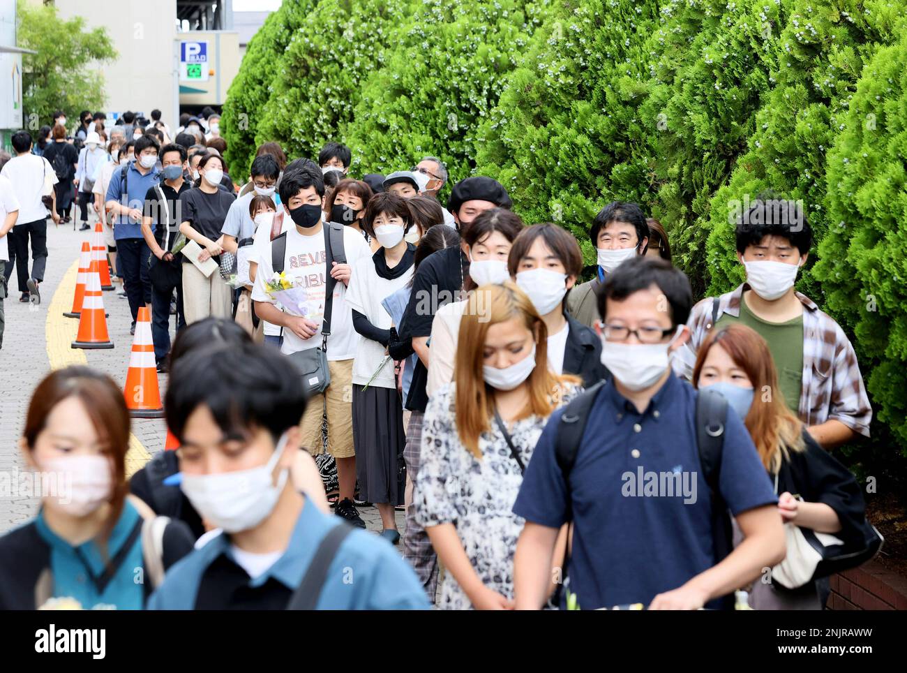 People shape a long line to offer flowers and prayers near a site where ...