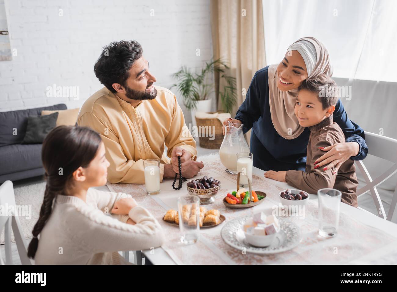 Femme afro-américaine souriante dans le hijab embrassant son fils près ...