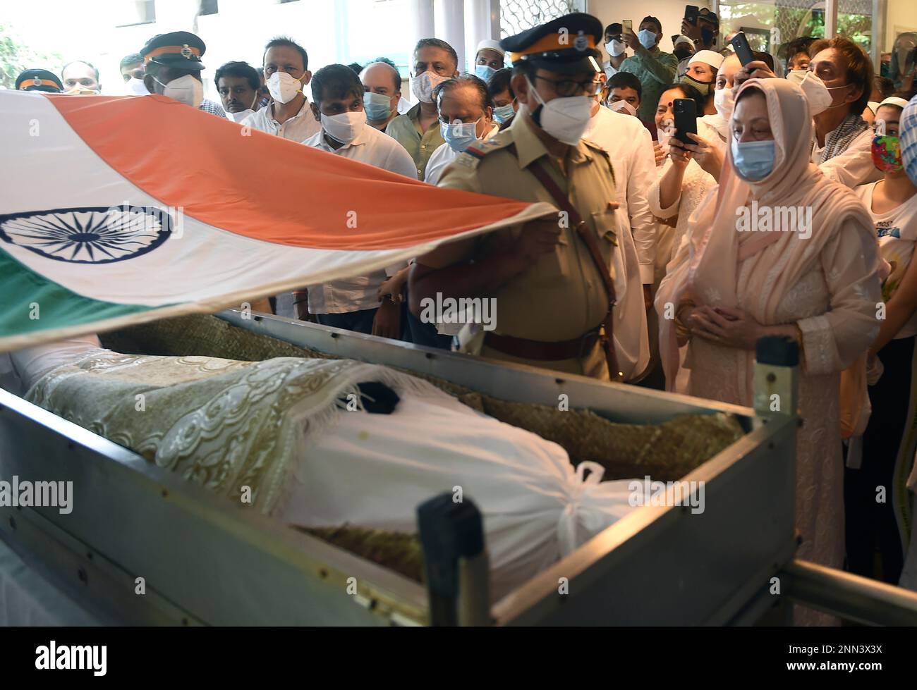 A police officer places an Indian national flag over the coffin of ...