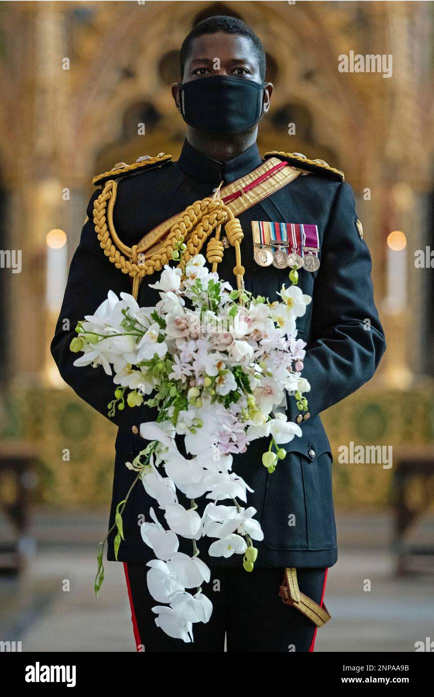 The Queen's Equerry, Lieutenant Colonel Nana Kofi Twumasi-Ankrah, carries a bouquet of flowers ...