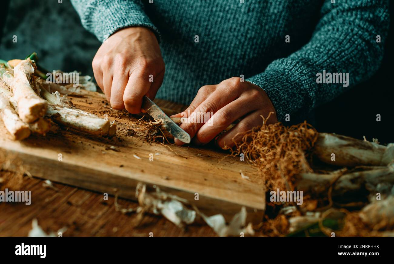 Un homme coupe les racines de quelques calcottes crues, les oignons ...