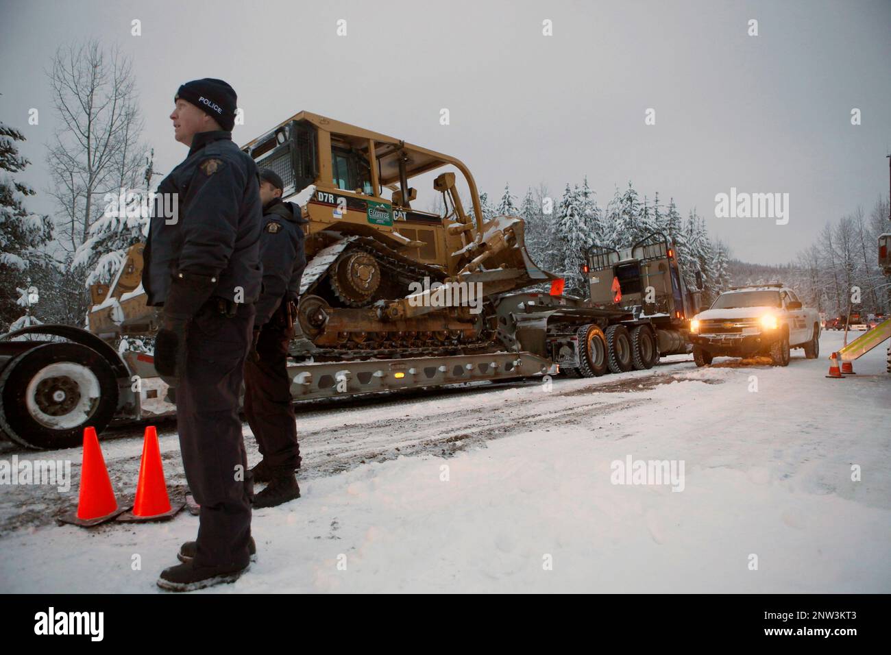 Royal Canadian Mounted Police (RCMP) officers look on as contractors ...