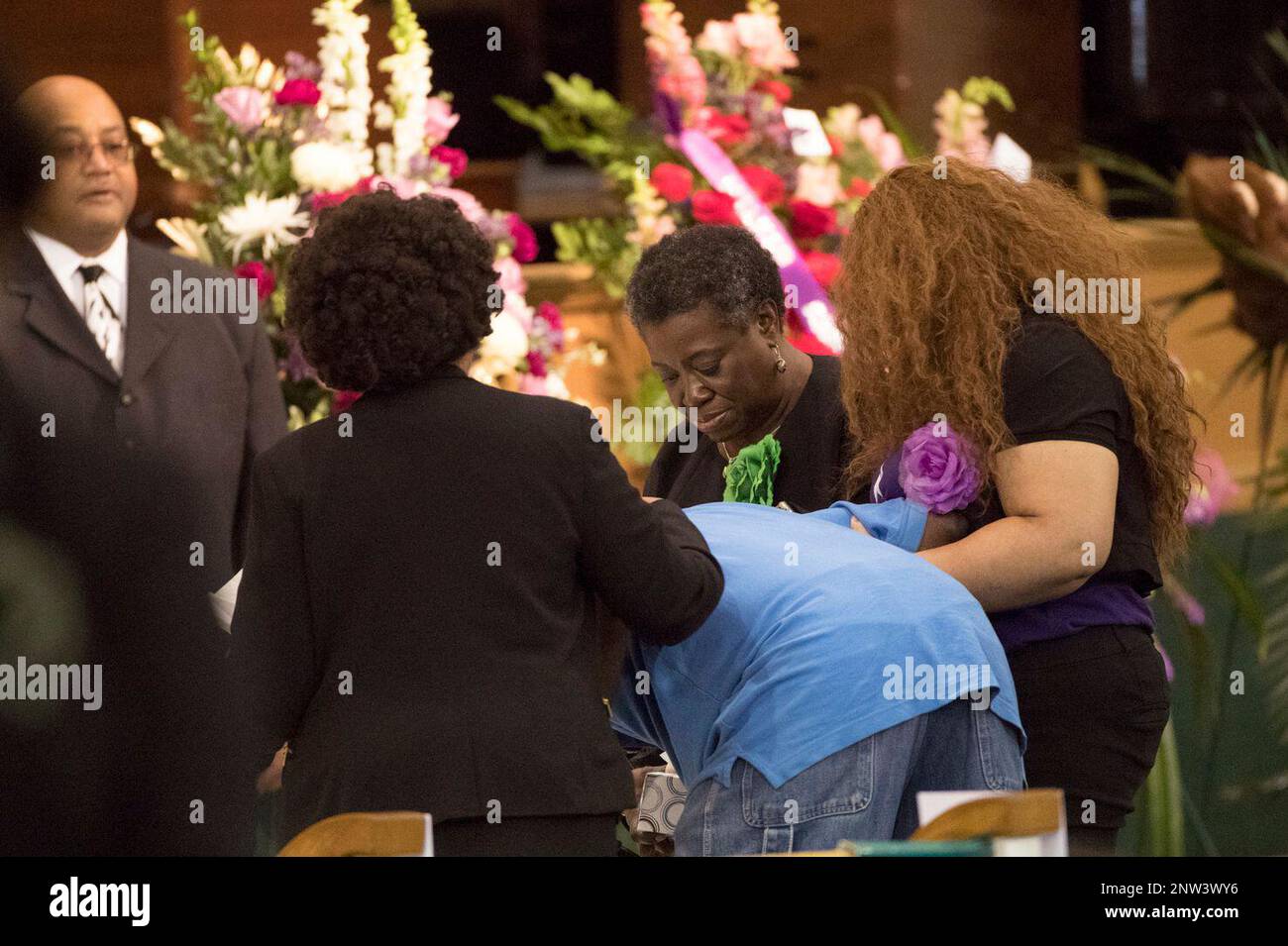Three women hold a man as he becomes emotional approaching the casket ...