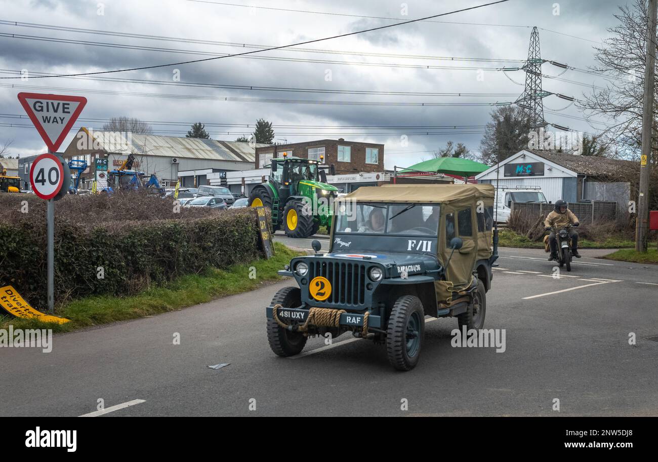 Une Jeep de WW2 ans peinte en livrée RAF arrondit un coin suivi d'une ...