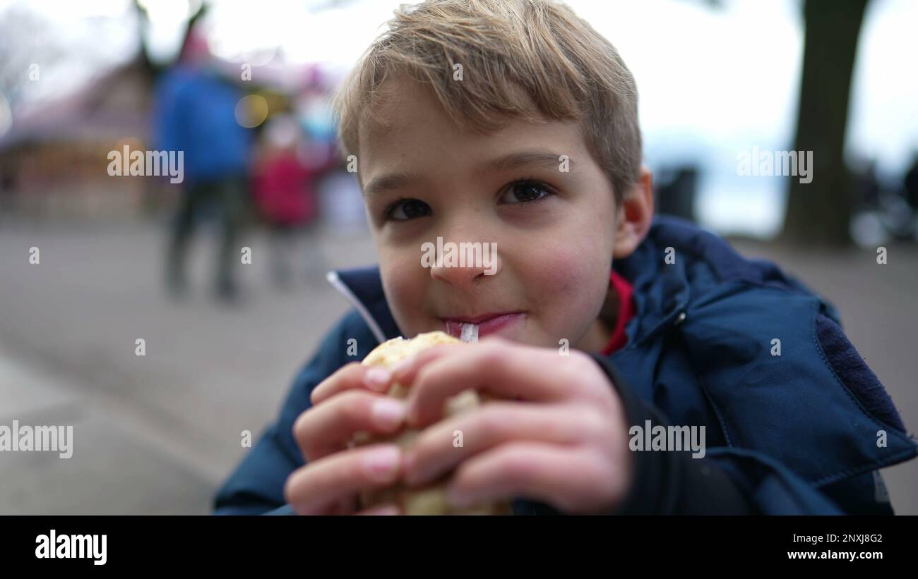 Petit garçon mangeant des crêpes dehors dans la rue de ville pendant la ...