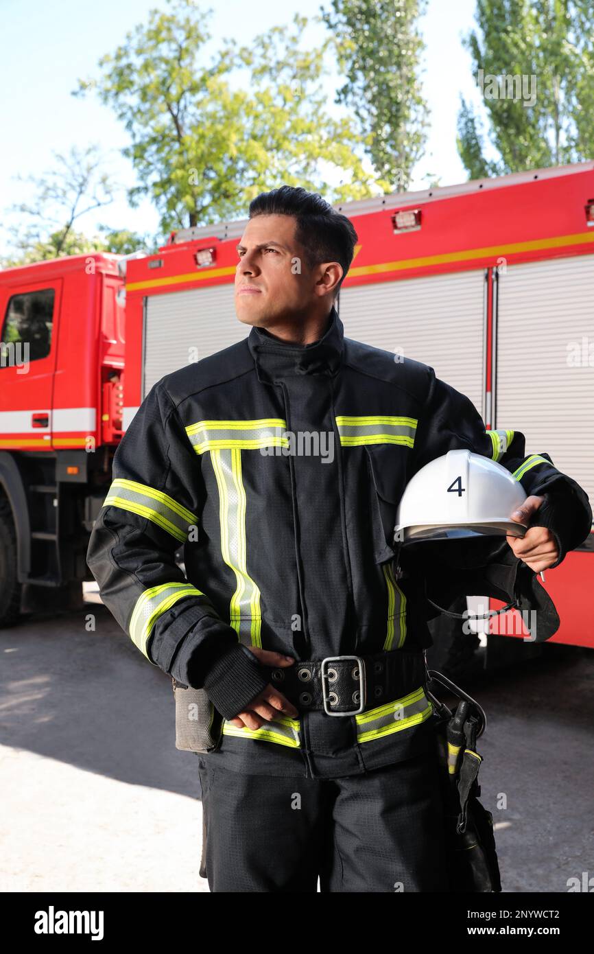 Portrait d'un pompier en uniforme avec un casque près d'un camion de ...