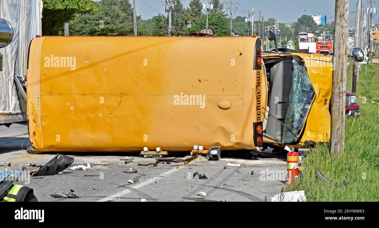 A damaged school bus lies on its side after a collision in East ...