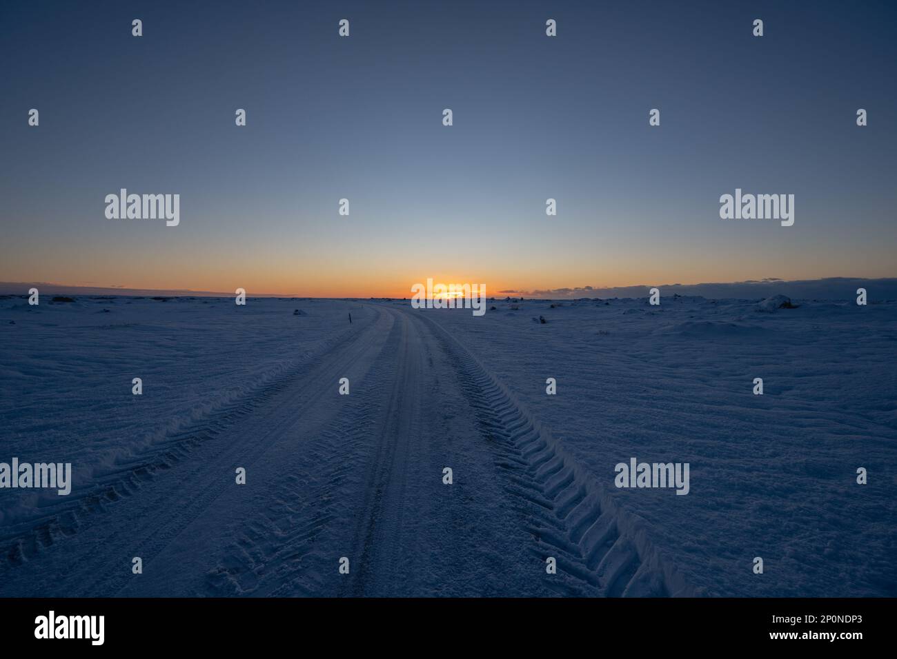 Route et paysage enneigé plat dans presque l'obscurité avec des traces ...