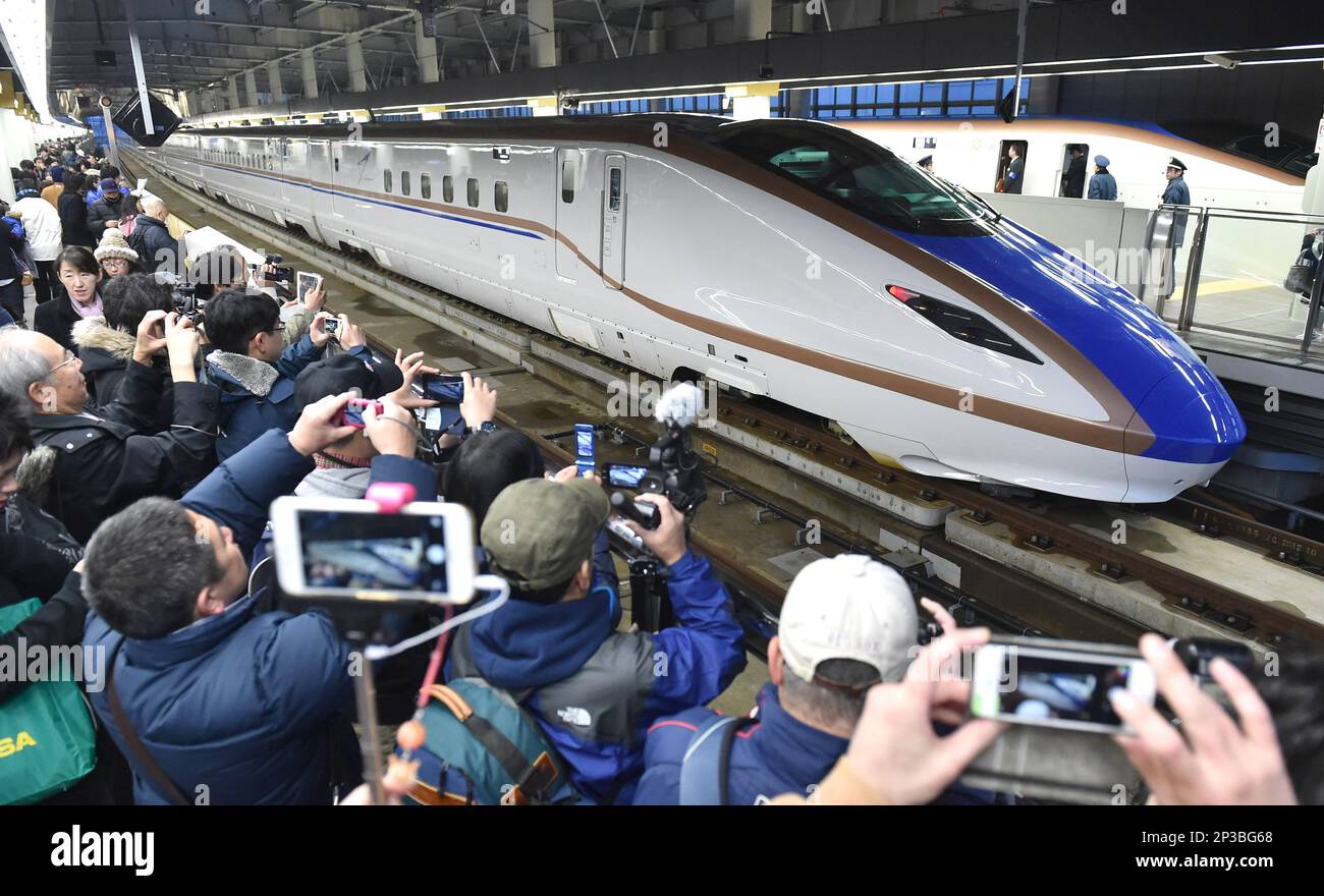 Train enthusiasts take phots of a bullet train on the Hokuriku ...