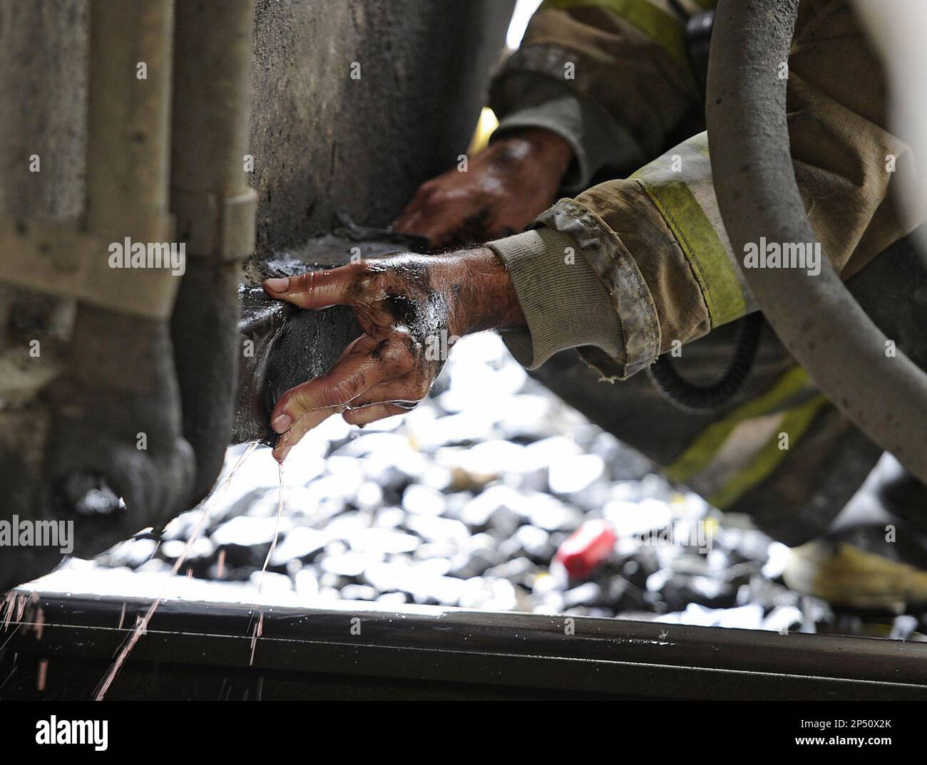 A firefighter tries to stop diesel fuel from spilling from a ruptured ...