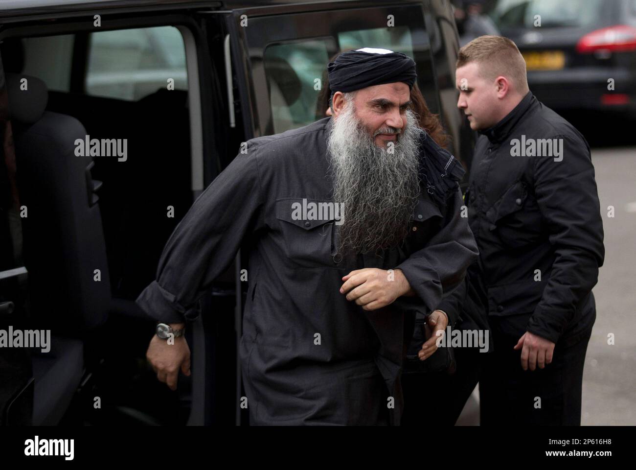 Abu Qatada, left, gets out of the rear of a vehicle as he returns to ...