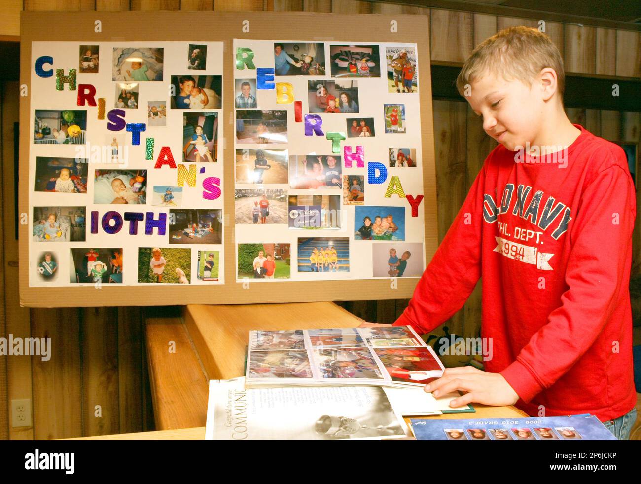 Christian Stone, 10, looks over a scrapbook of his baby photos at his ...