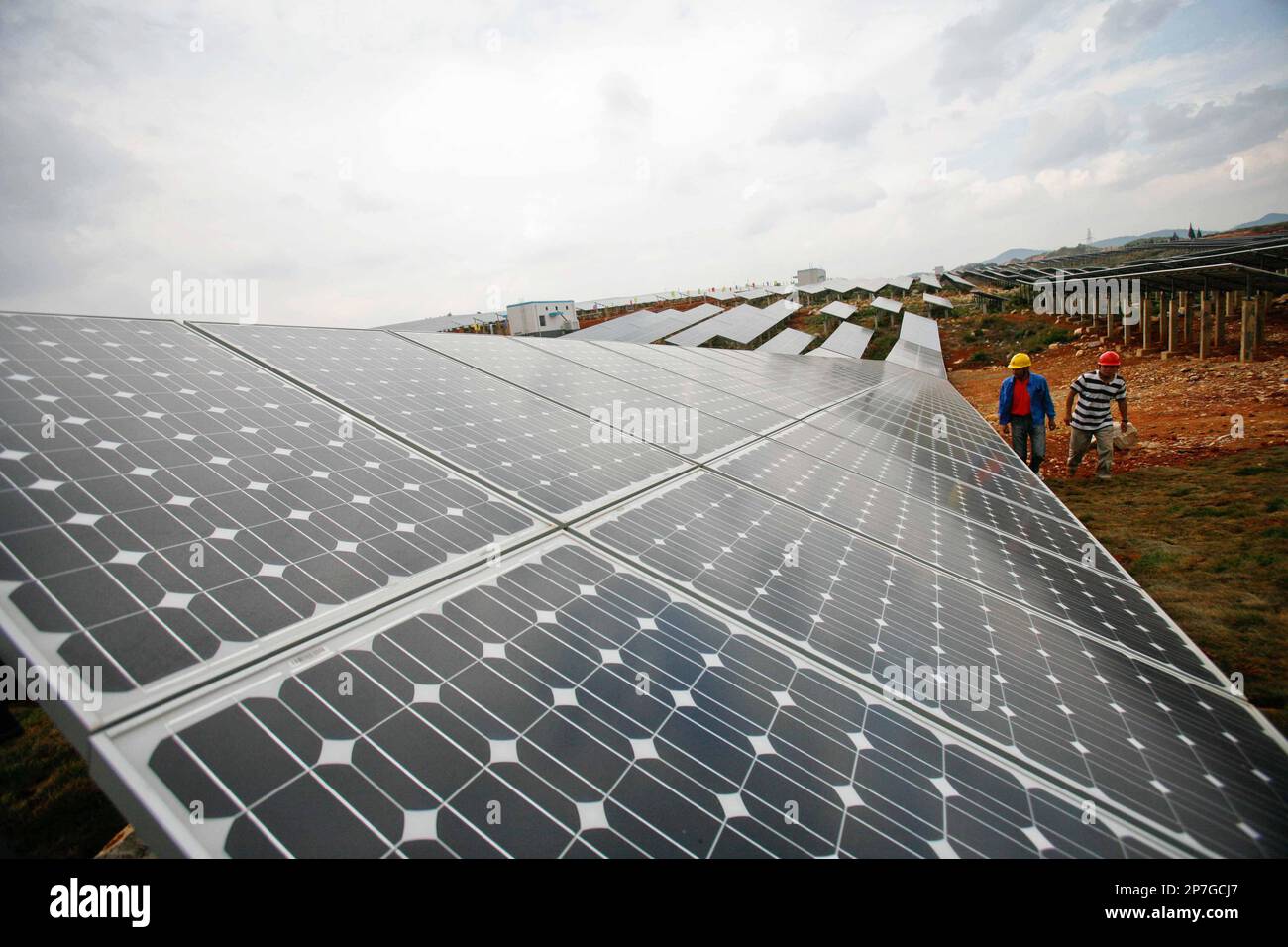 Workers walk in the 20-megawatt solar farm, the first phase of the ...