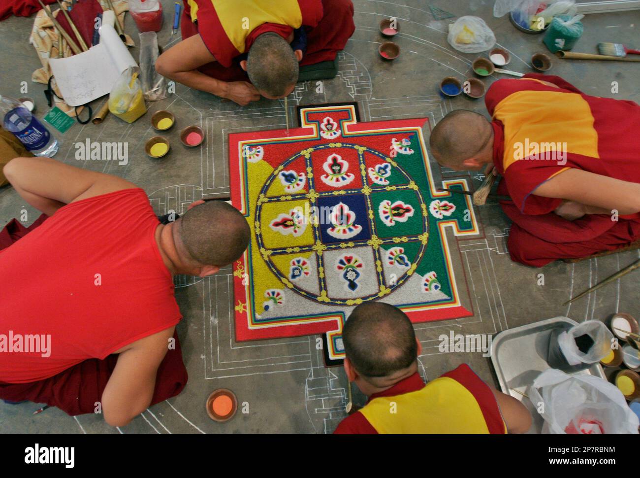 Tibetan exiles prepare an art work on the floor using colored powder at ...